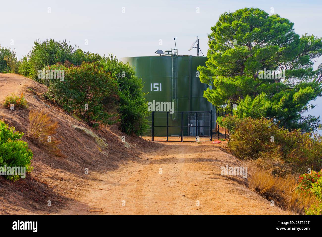 Scenic dirt pathway leading to a green water tank in Griffith Park ...