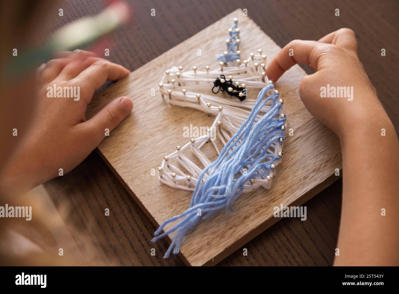 Child creates intricate string art. Fostering focus, creativity ...