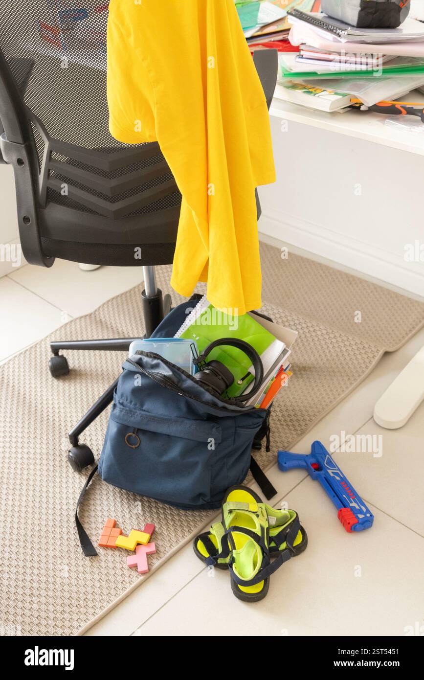 Disorganized teenager study space with cluttered desk and backpack. A ...