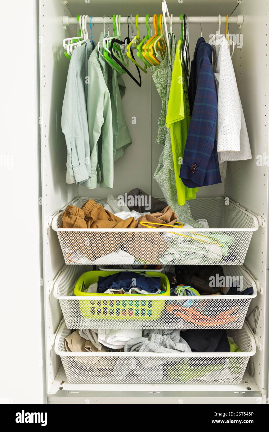 Boy closet with hanging clothes and mesh baskets for tidy storage in an ...