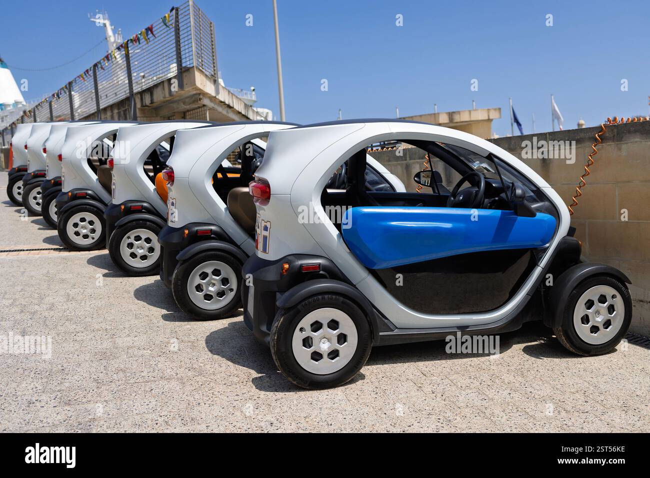 A row of compact electric cars charging outdoors, showcasing eco ...