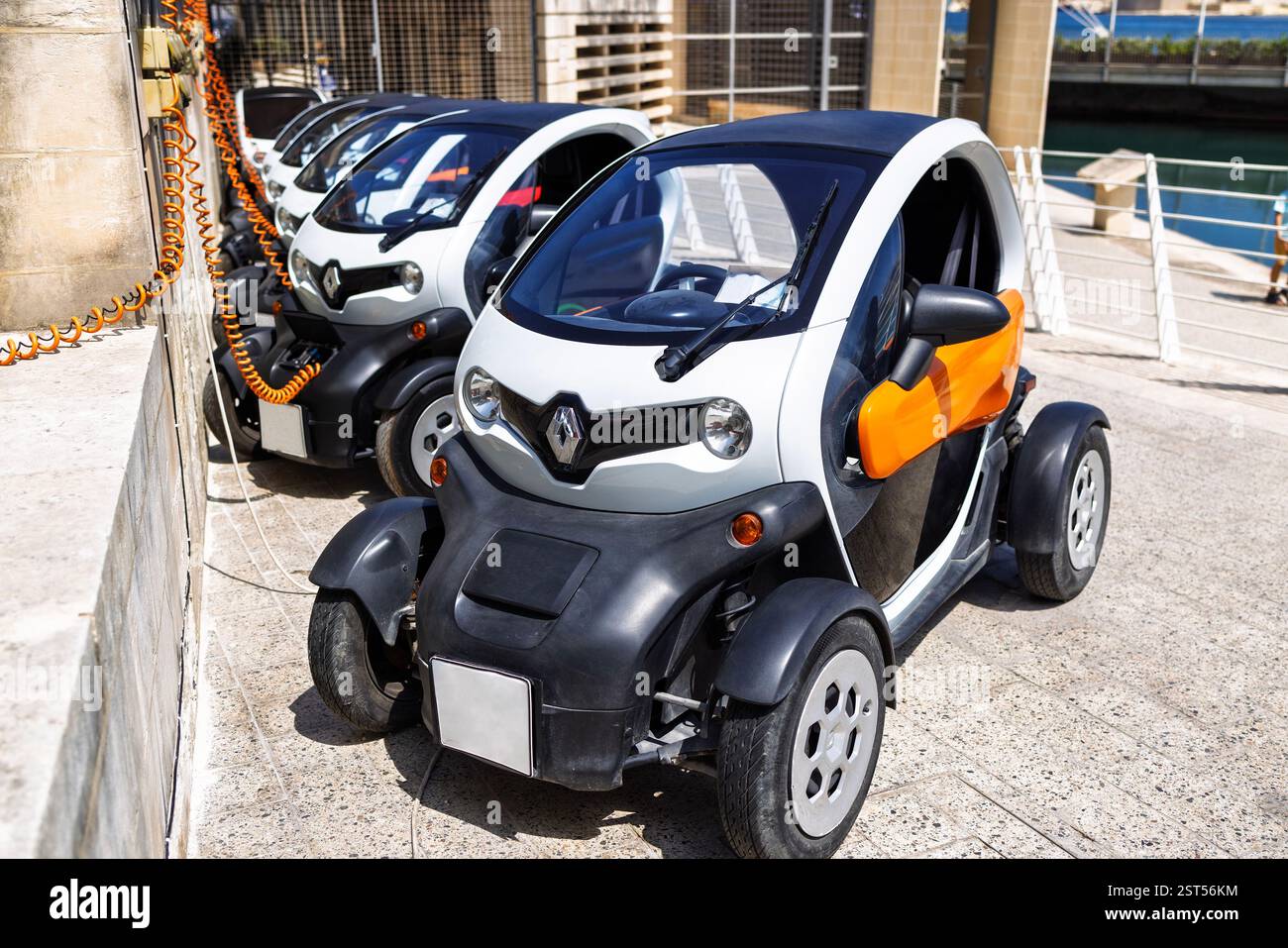 A line of small electric cars charging outside, highlighting ...