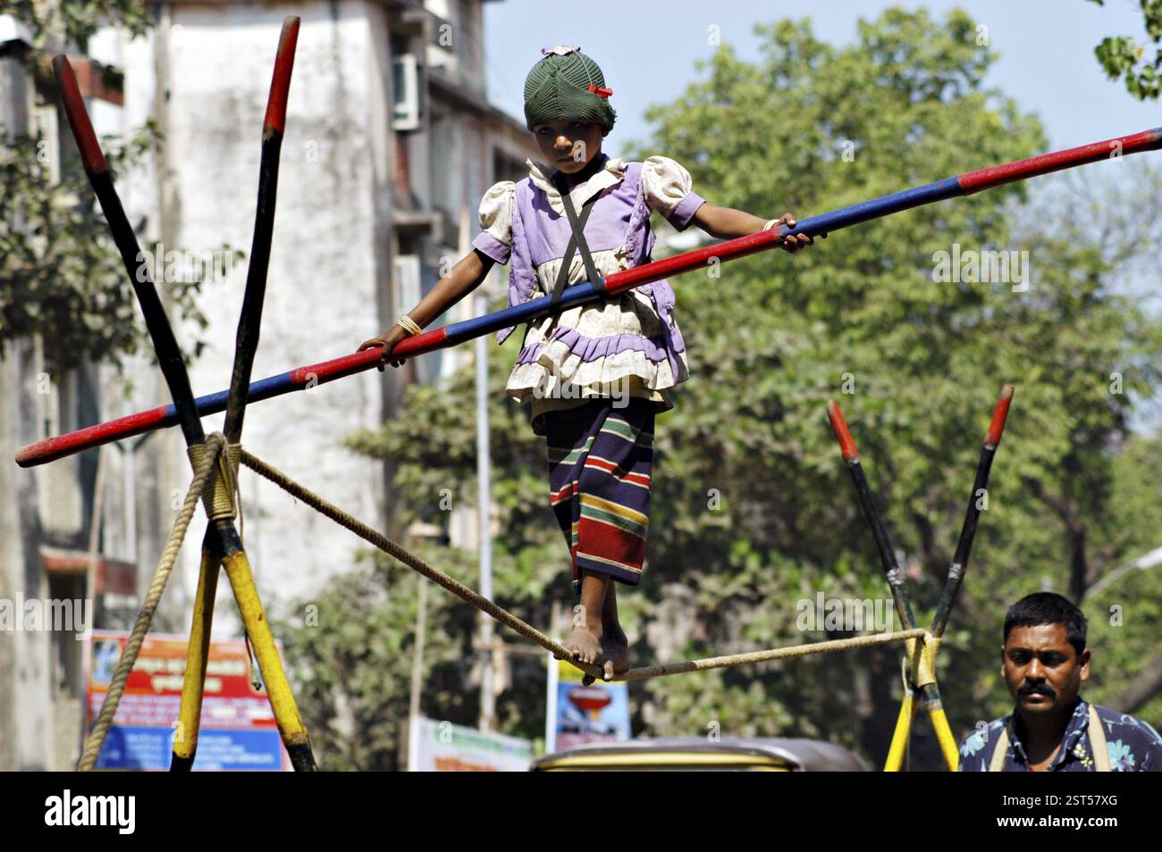 South Asian girl working street performer balancing act by walking on ...