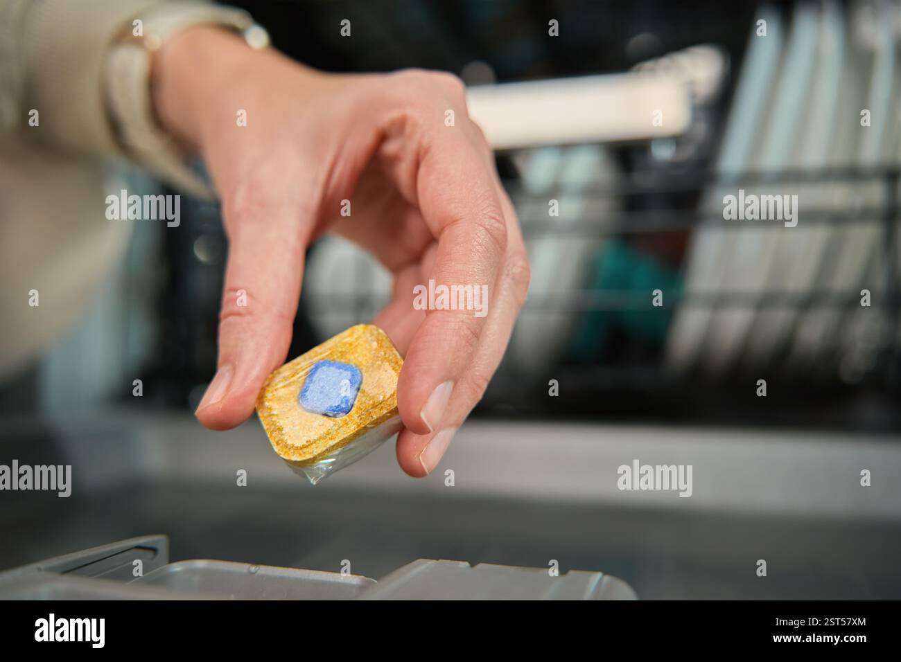 Close-up of female hand placing dishwasher detergent tablet into ...