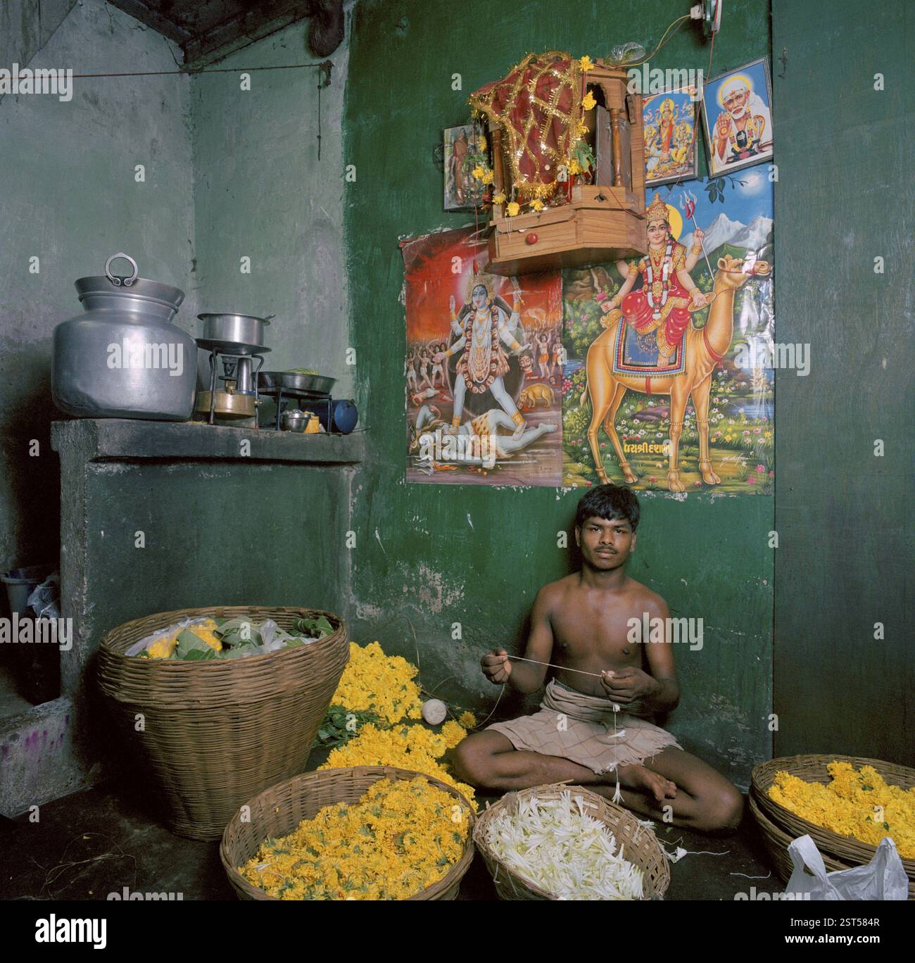 A flower garland maker in a small room in a slum which doubles for ...