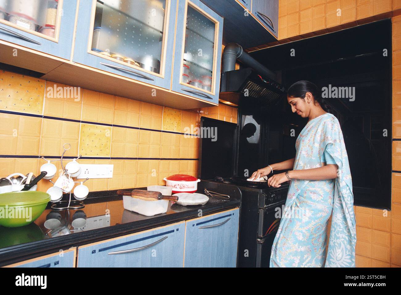 South Asian Indian Woman working in kitchen cleaning cooking range ...