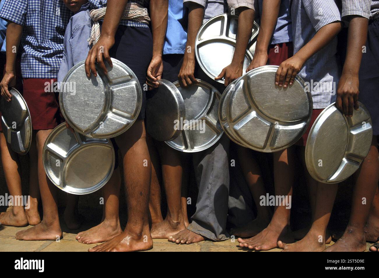 Children standing in queue with round molded stainless steel plate for ...
