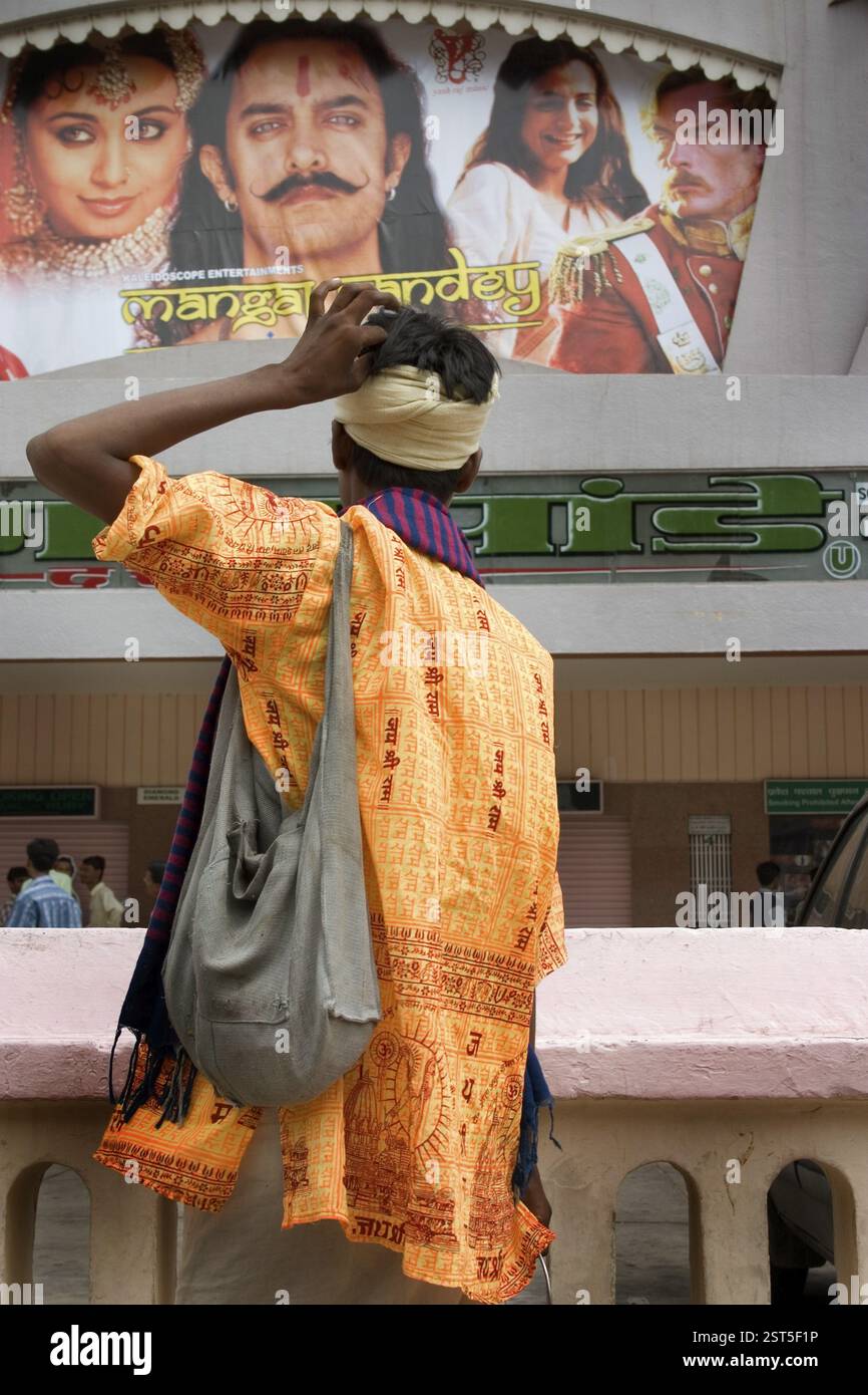 A orange clad religious sadhu looking at the poster at Raj Mandir cinem ...