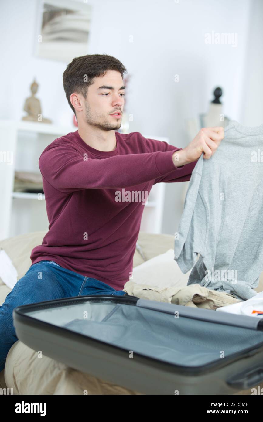 young man packing his suitcase in a hotel room Stock Photo - Alamy