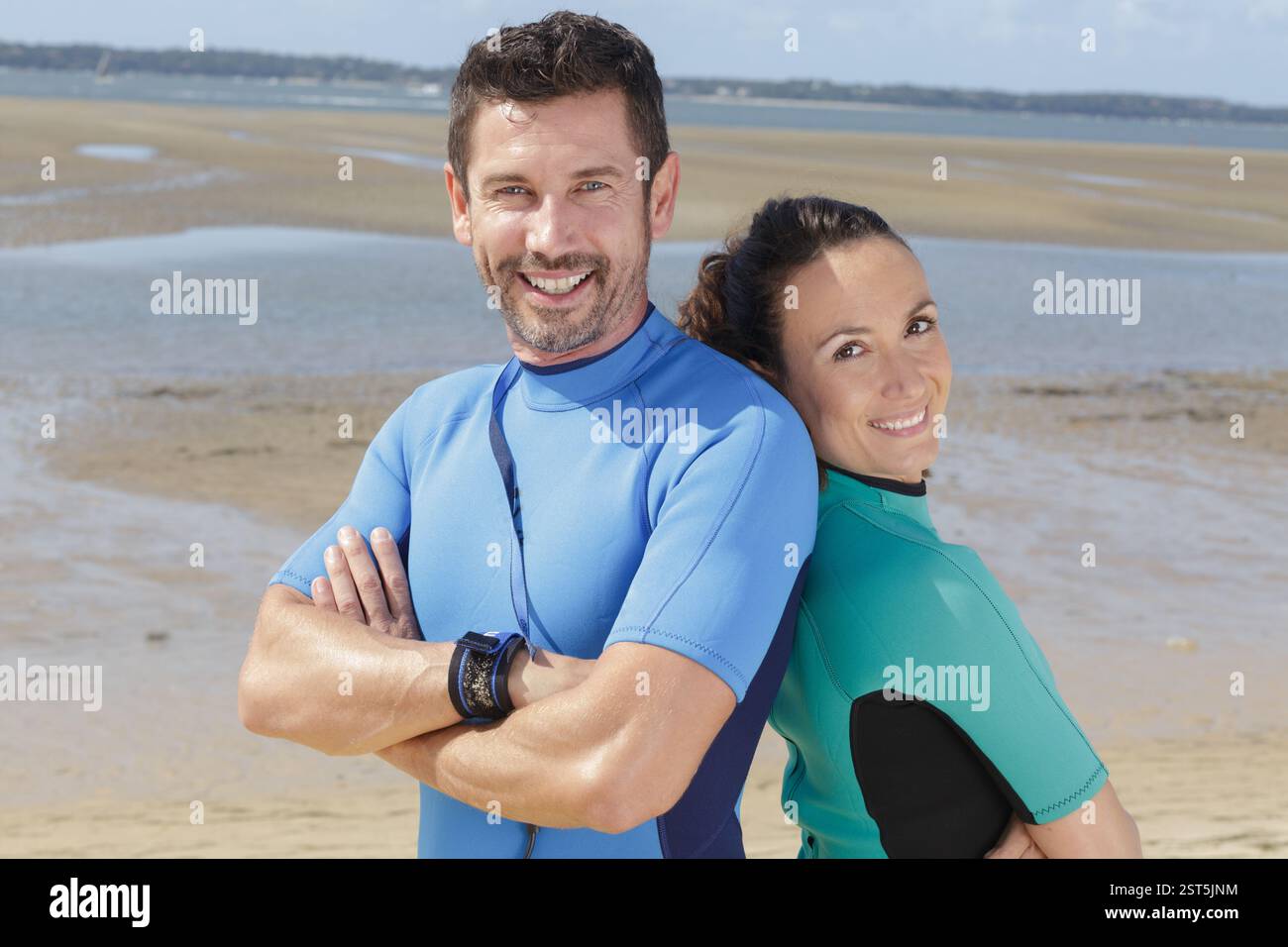 surfing couple back to back on the beach Stock Photo - Alamy