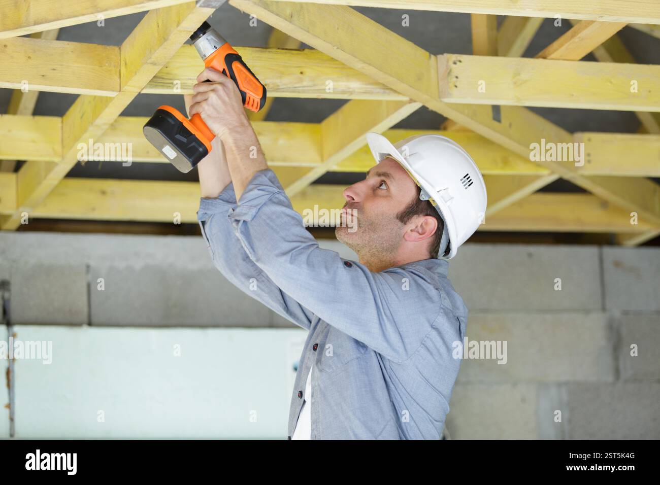 man in construction helmet fix clapboard on ceiling Stock Photo - Alamy