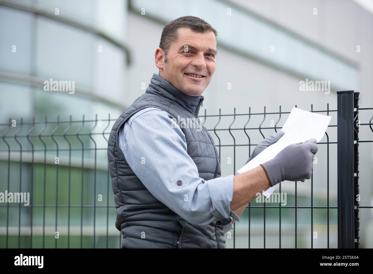 handyman outdoors mounting a fence Stock Photo - Alamy
