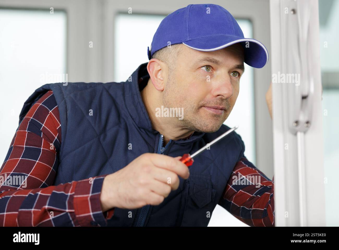 service man installing window with screwdriver Stock Photo - Alamy
