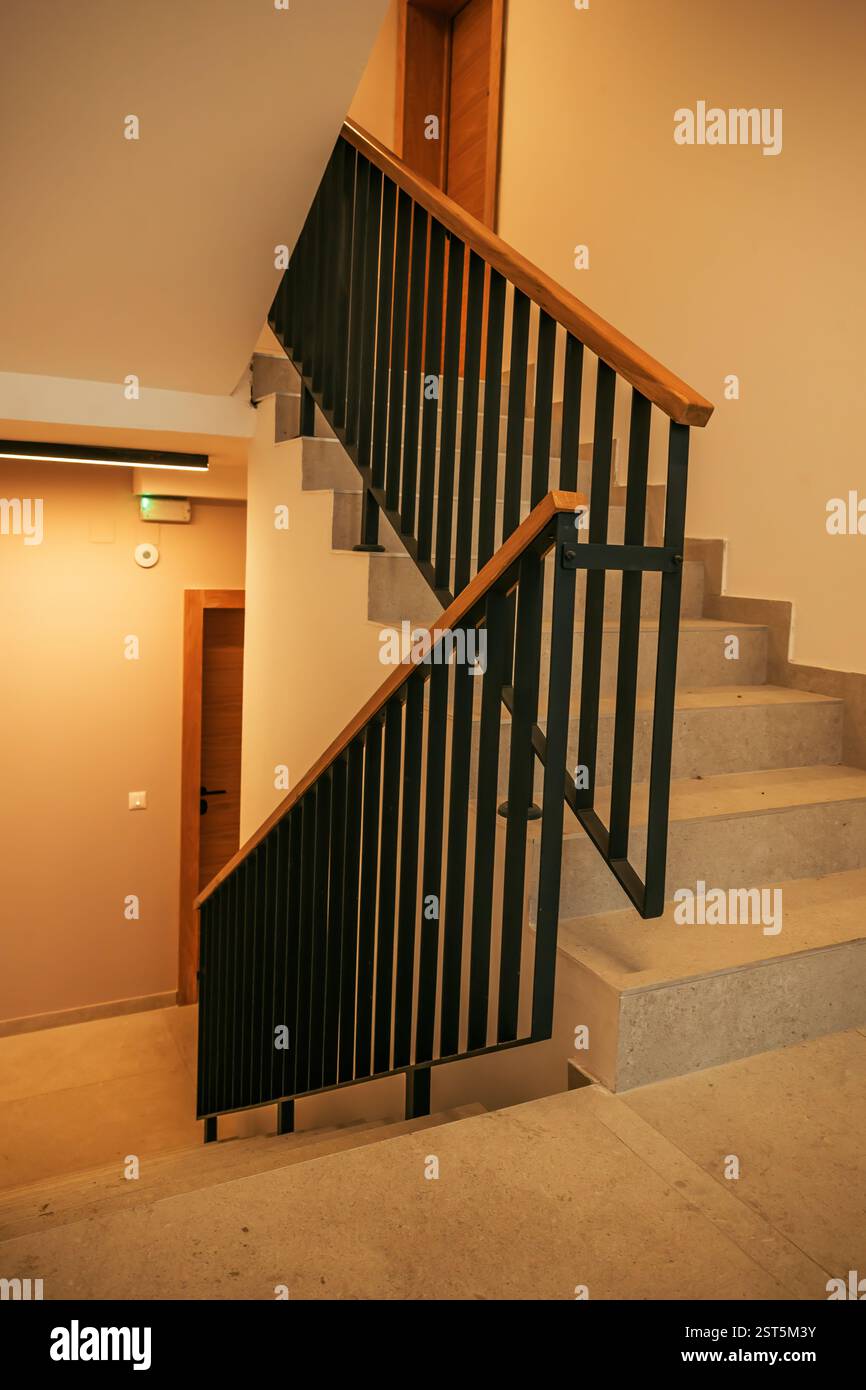Stairs in modern apartment building with still bars and wooden railing ...