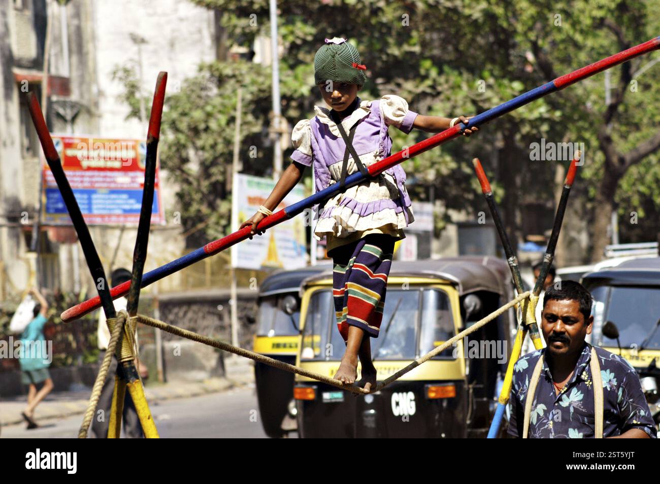 South Asian girl working street performer balancing act by walking on ...
