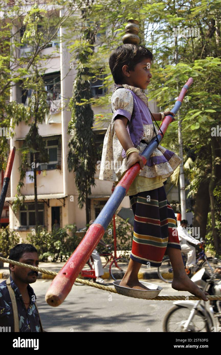 South Asian girl working street performer balancing act by walking on ...