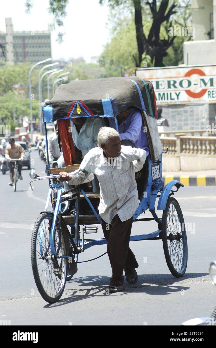 A old cycle rickshaw puller carrying passengers at Nagpur, Maharashtra ...
