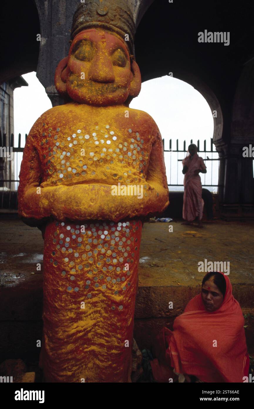 Tall orange red statue of demon Malla who had converted from a demon to ...