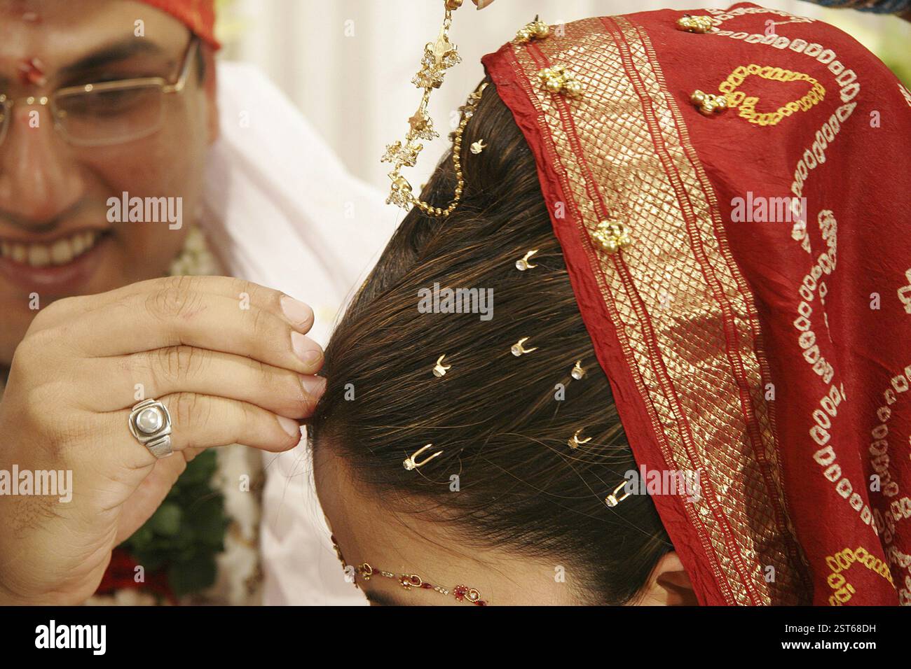Indian Gujarati Bridegroom putting red powder called 'Sindoor' on the bride's forehead as ritual ...