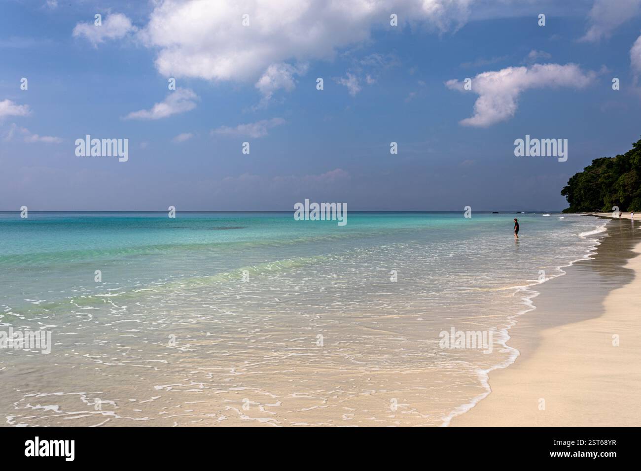 one person is distance, walking into ocean, showing he beauty of ...