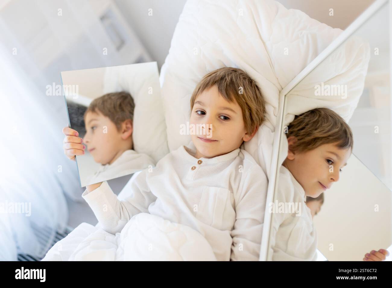 Portrait with mirrors of a child, lying in bed, reflection of his face ...