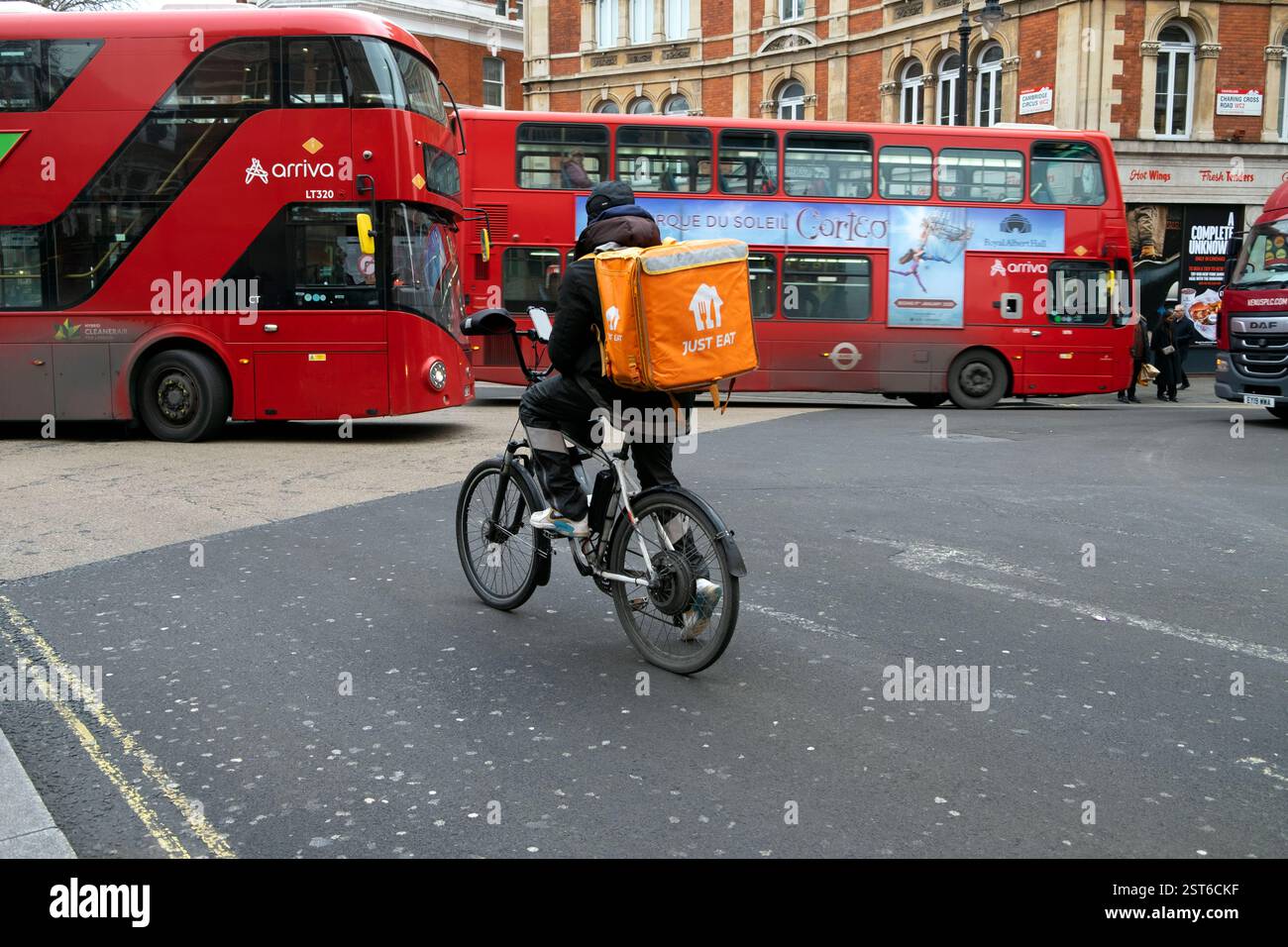 Just Eat food delivery courier with orange pack on back riding bike and ...