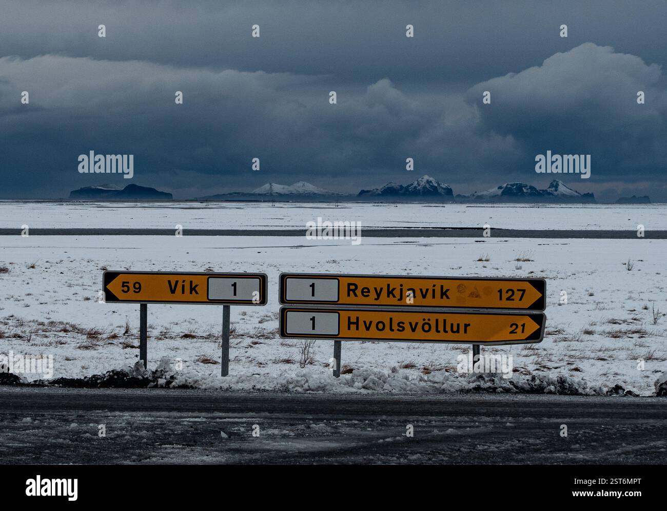 Directional road signs covered in snow featuring distant mountains and ...