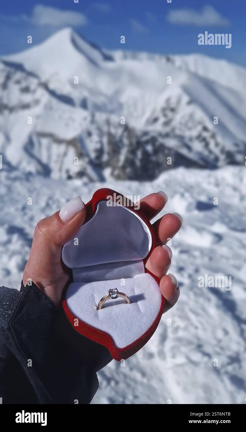 Female hand closeup holding an engagement ring inside a red heart ...