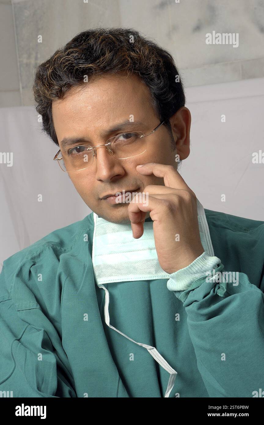 Young Indian Doctor surgeon, serious, in green operation theatre coat ...