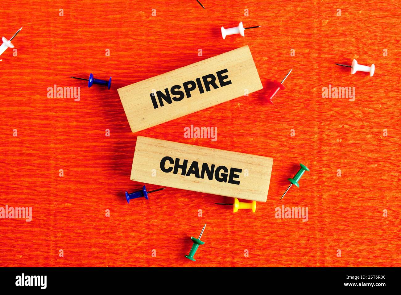 Wooden blocks display the words inspire and change amidst colorful push ...