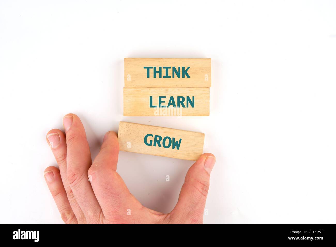 A hand holds wooden blocks with the words think, learn, and grow ...