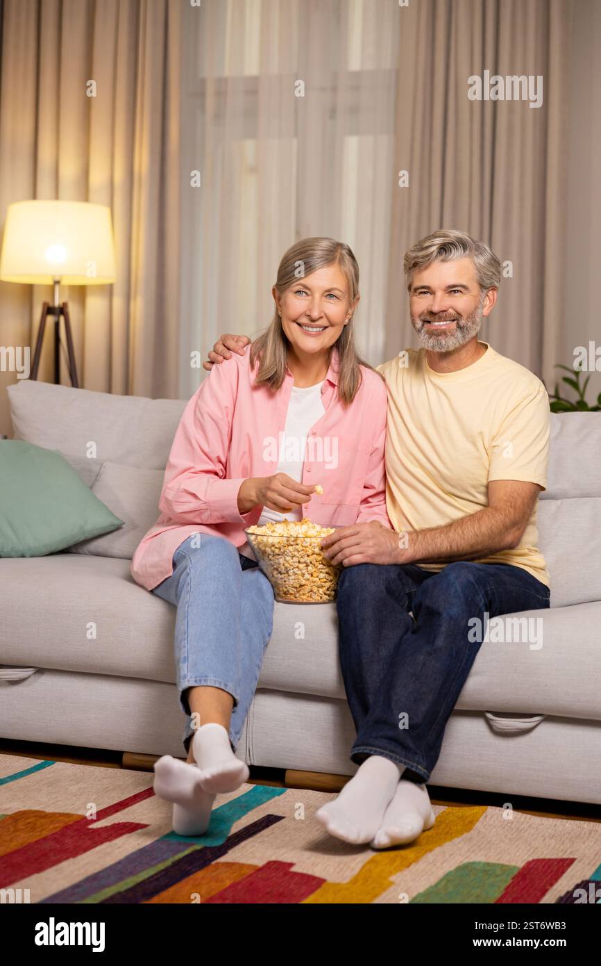 Mature happy couple eating popcorn and watching a movie Stock Photo - Alamy