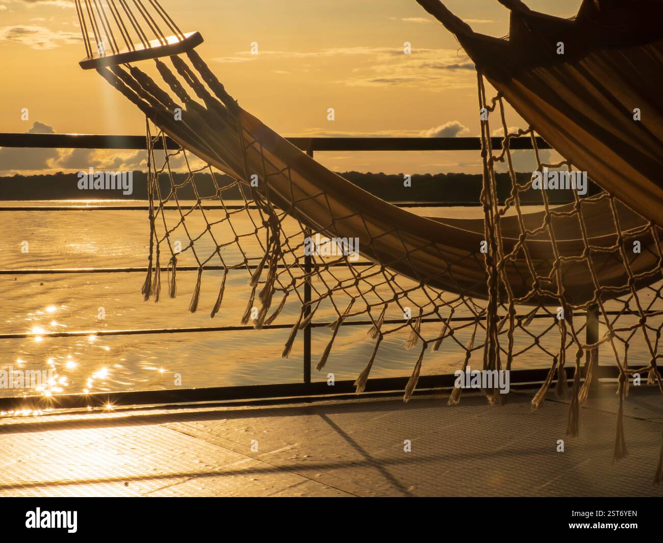 Sunset and hammocks on board a luxury tourist ship sailing the Amazon ...
