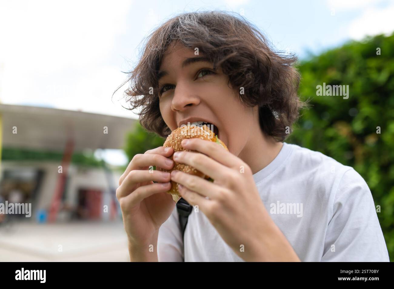 Hungry student eating burger for lunch and looking happy Stock Photo ...