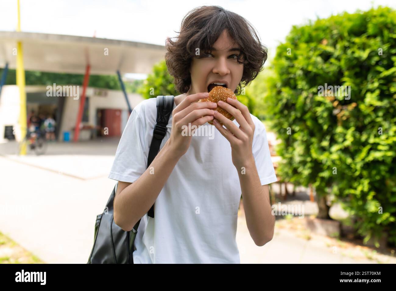 Hungry student eating burger for lunch and looking happy Stock Photo ...