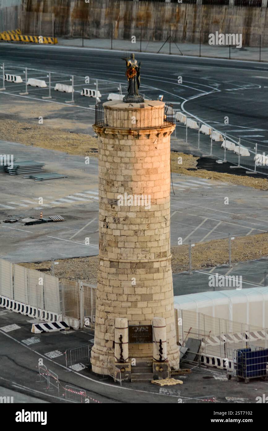 A historic stone watchtower with a statue on top, standing in the port ...