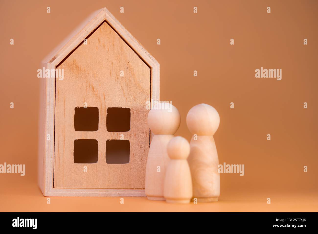 Wooden figurines resembling a family beside a small wooden house model ...