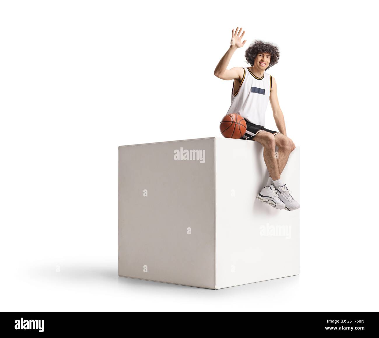 Basketball player sitting on a white cube and waving isolated on white ...