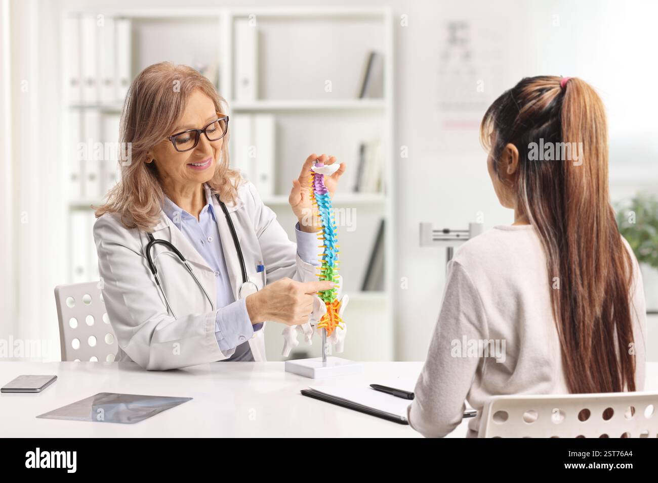 Female orthopedic doctor and a patient at the office looking at a human ...
