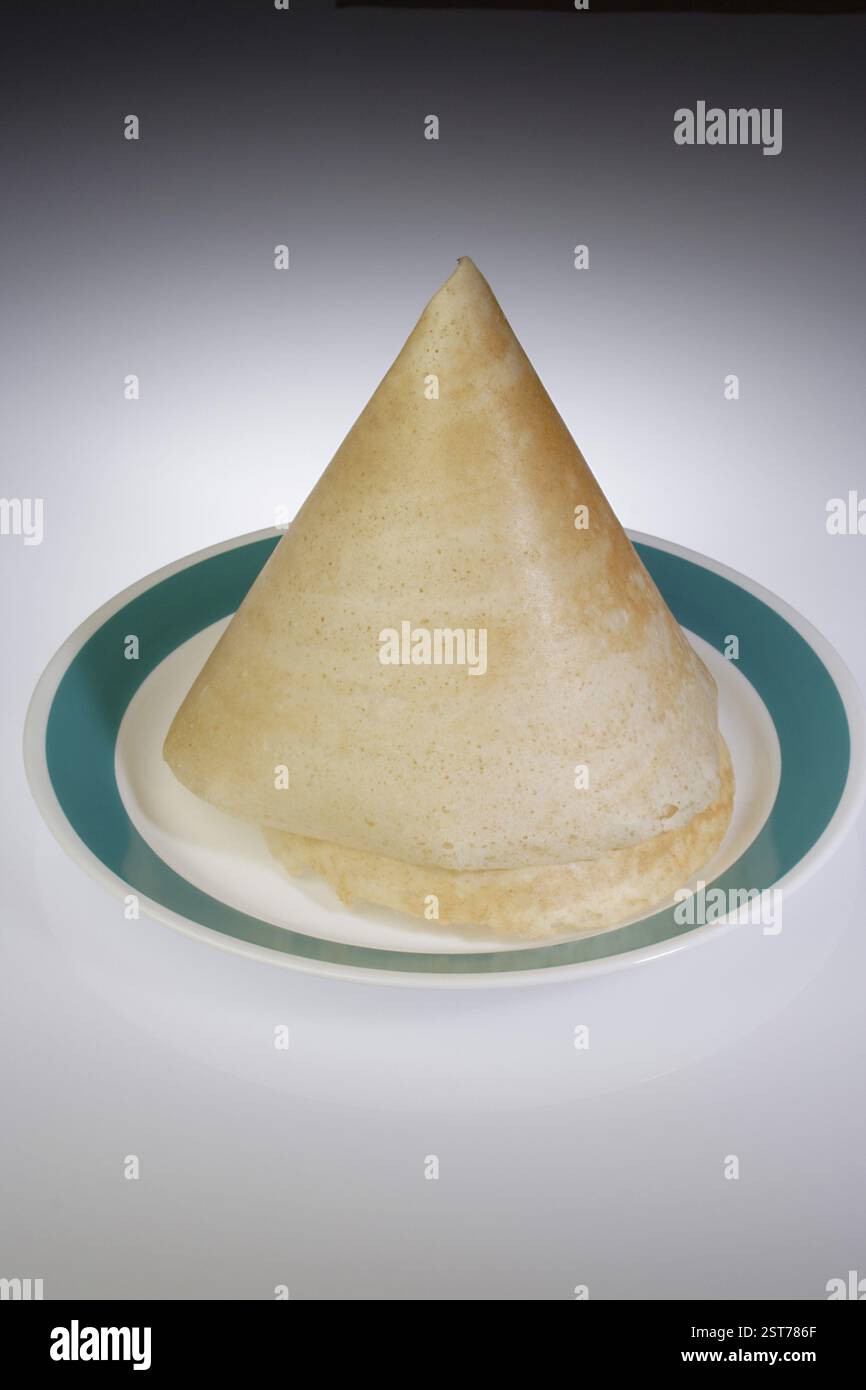 Indian snack fast food dosa in cone shape on a plate against white ...