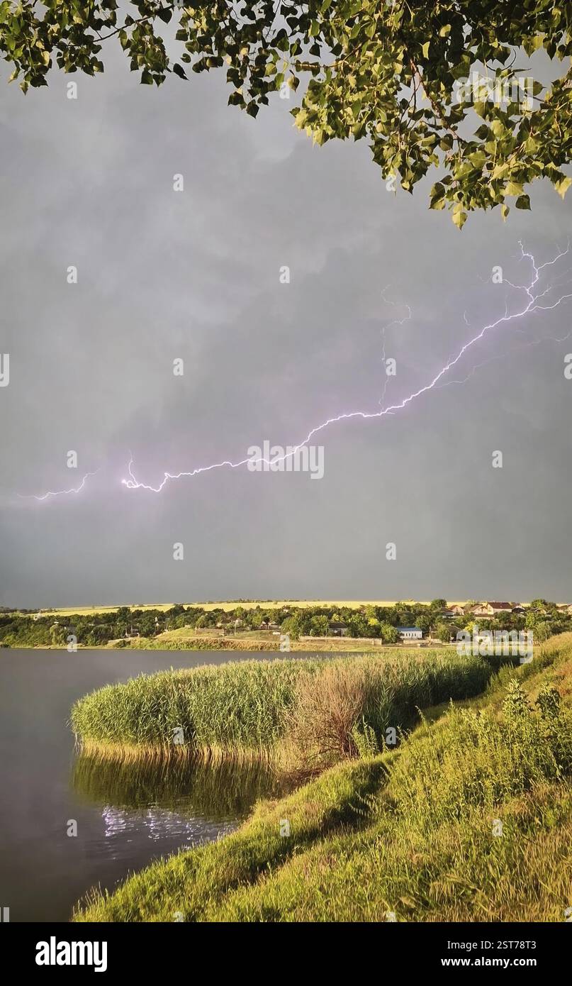 Massive storm formation with lightnings in the sky above a countryside ...
