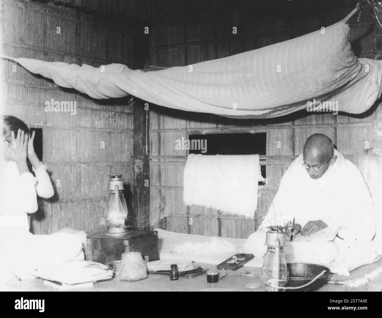 Mahatma Gandhi at work in the dim light of a kerosene lamp in West ...