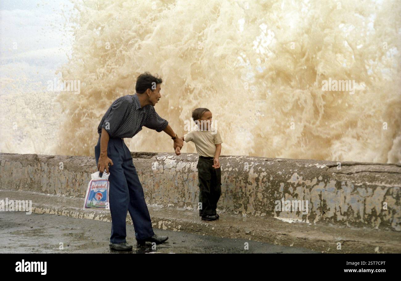 Father and son enjoy the huge sea waves lashing on the Marine Drive ...