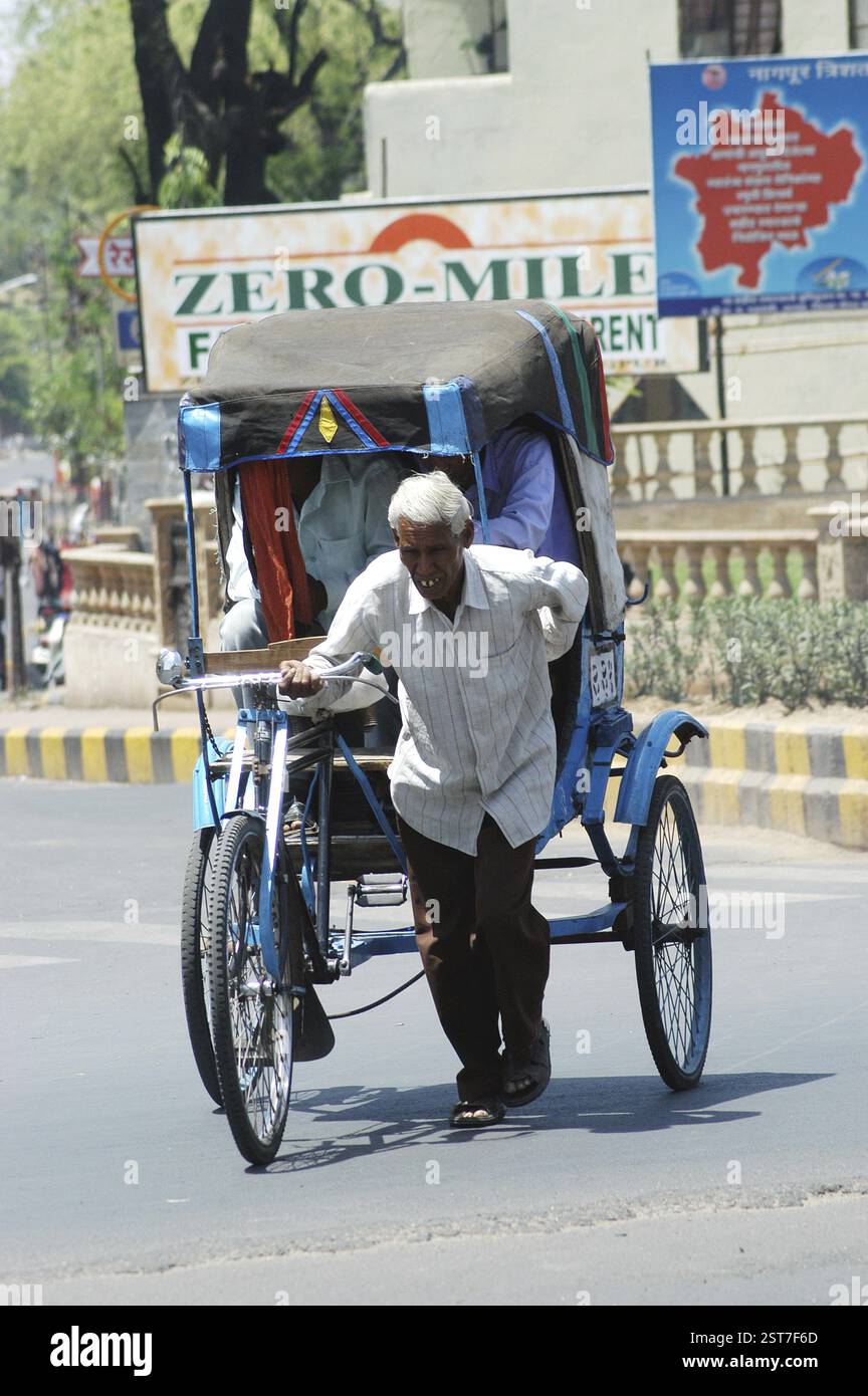 A old cycle rickshaw puller carrying passengers at Nagpur, Maharashtra ...