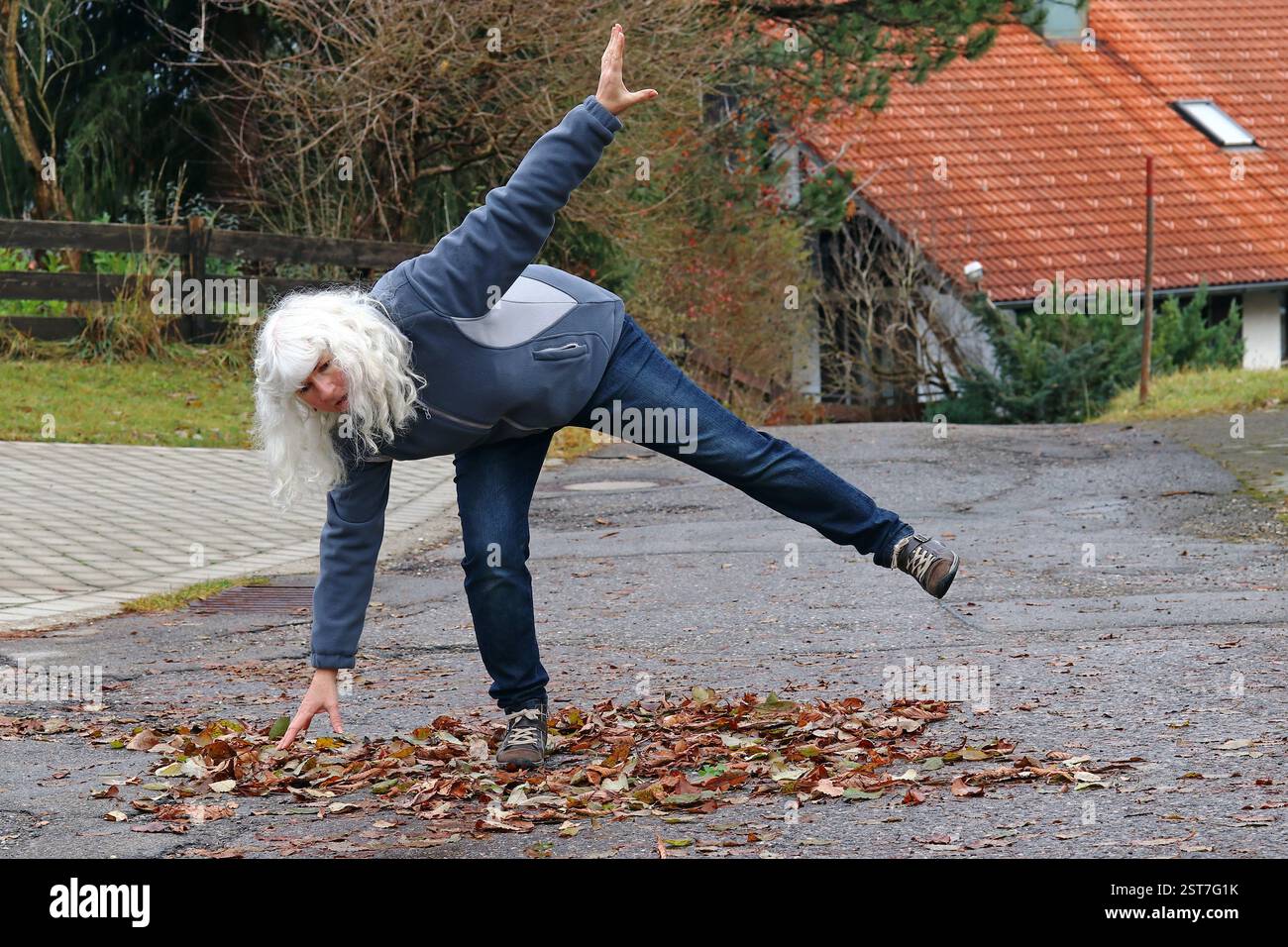 Slip hazard in fall and winter. An elderly woman slips on wet leaves on ...