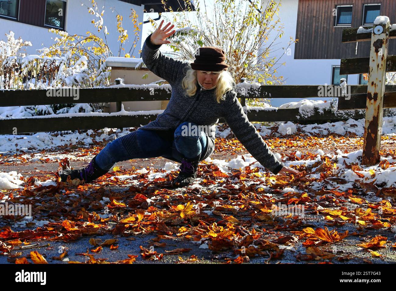 Slip hazard in fall and winter. An elderly woman slips on wet leaves on ...