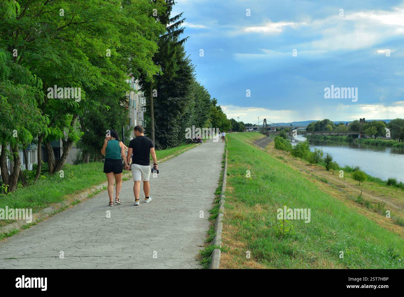Young couple holding hands while walking along the river Stock Photo - Alamy
