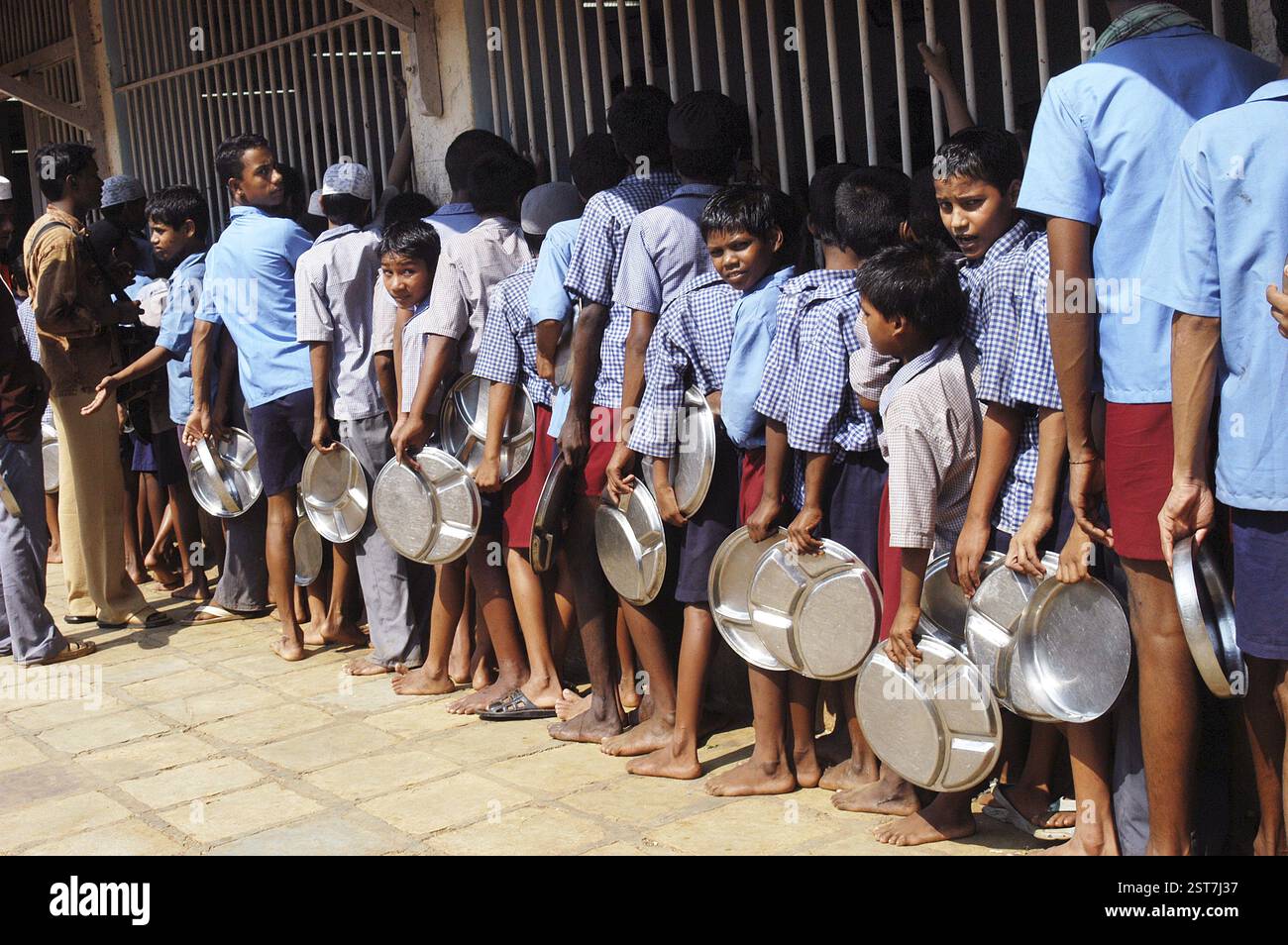 Children standing in queue with round molded stainless steel plate for ...