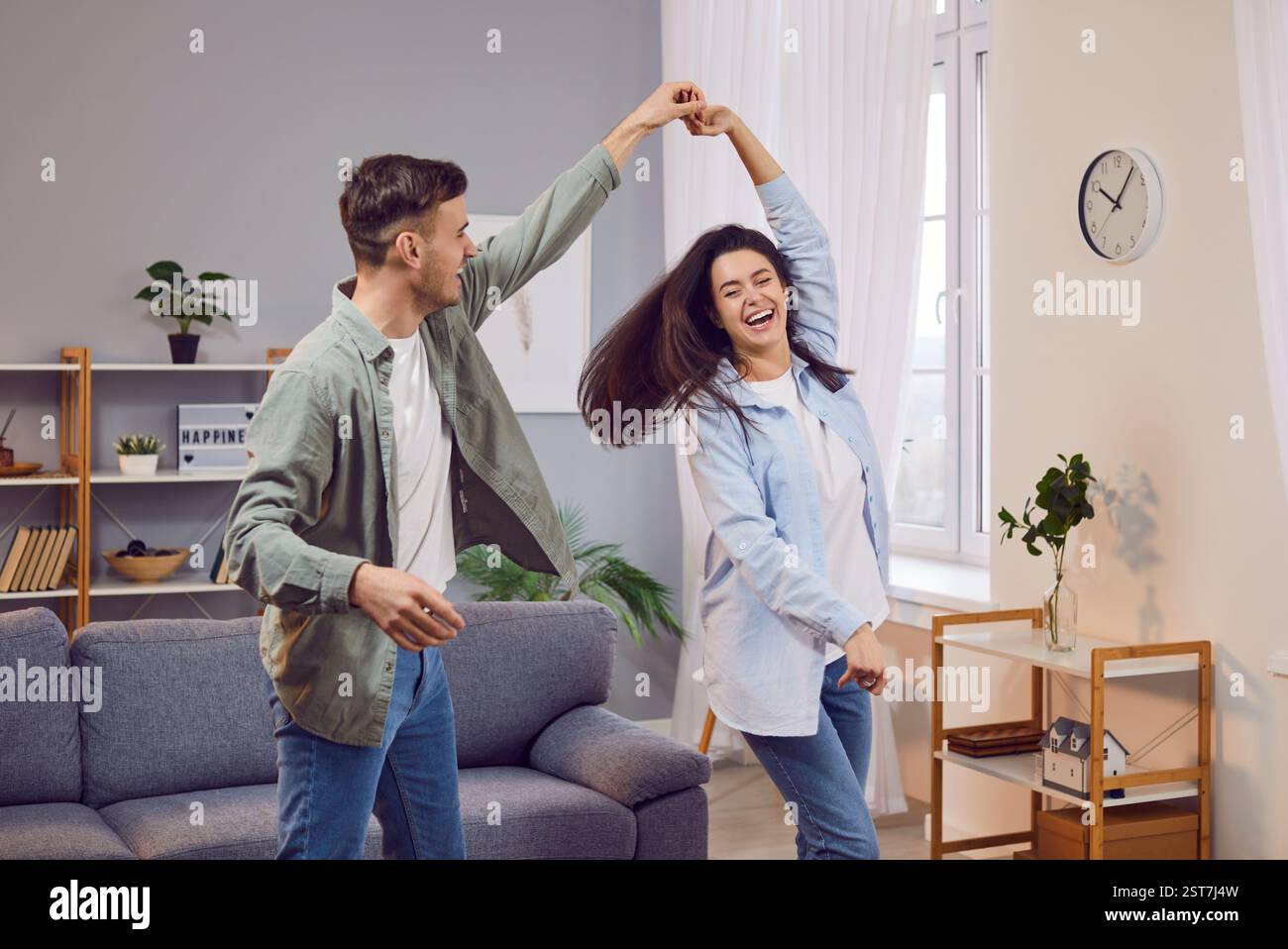 Happy laughing young couple having fun dancing at home in living room ...