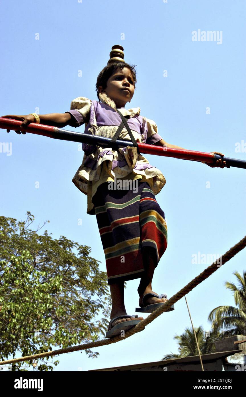 South Asian girl working street performer balancing act by walking on ...